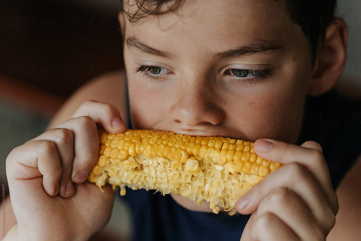 "Young Boy Eating Corn" by Stocksy Contributor "Irina Polonina" - Stocksy