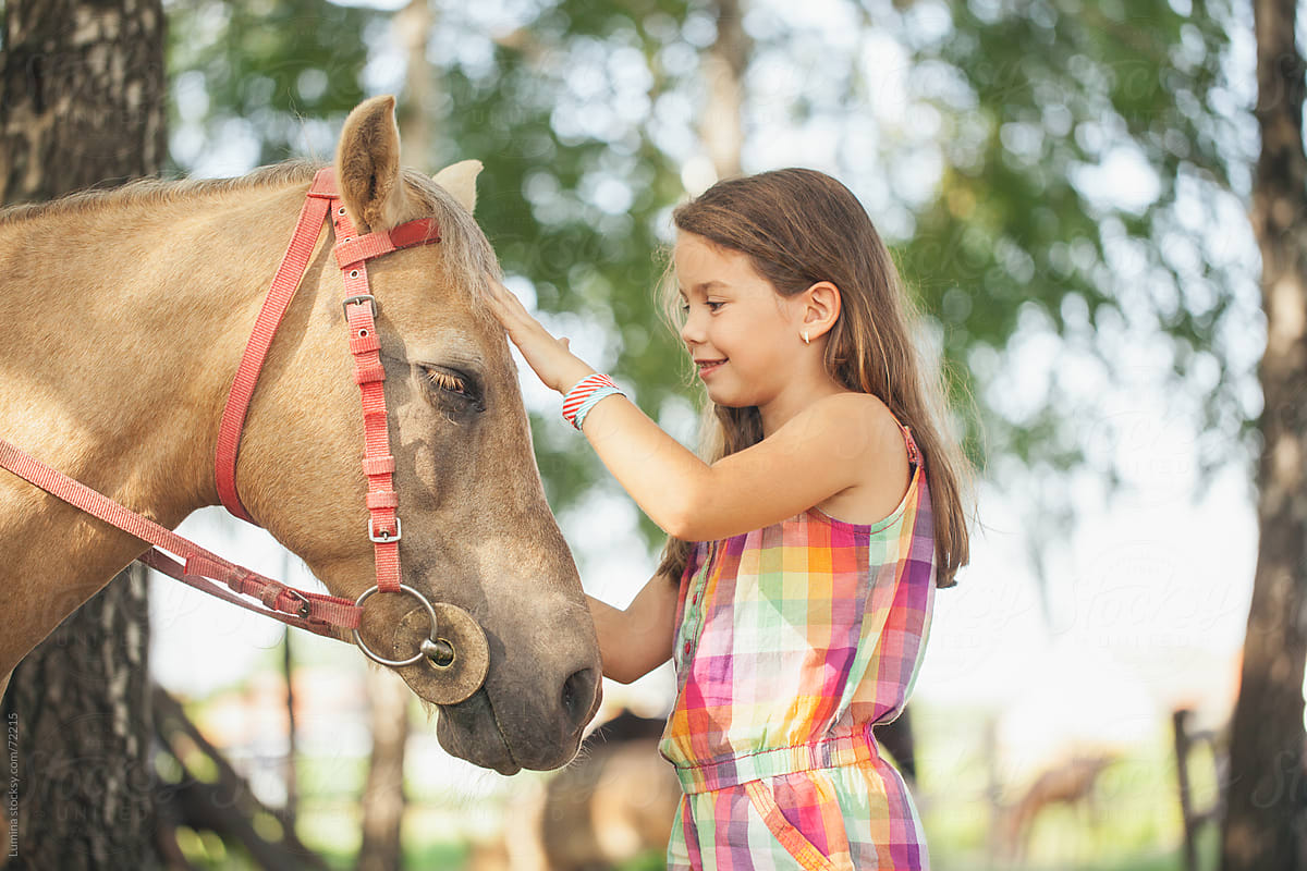  Smiling Girl Petting A Horse Del Colaborador De Stocksy Lumina