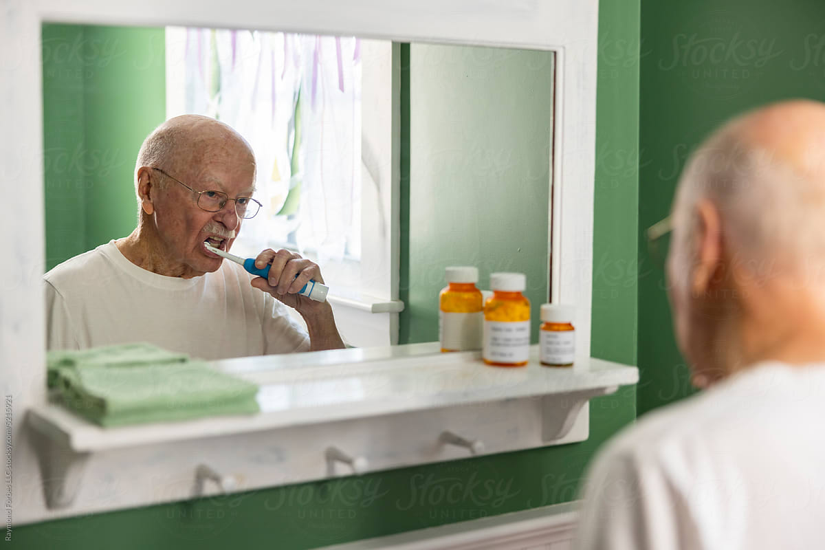 "Senior Citizen Man Brushing Teeth At Home With Prescription Bottle" by ...