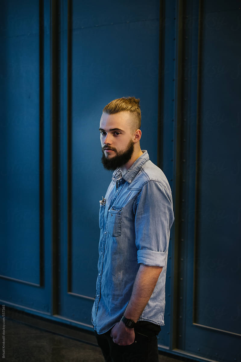 "Portrait Of Young Bearded Man Standing Against The Blue Wall" by ...