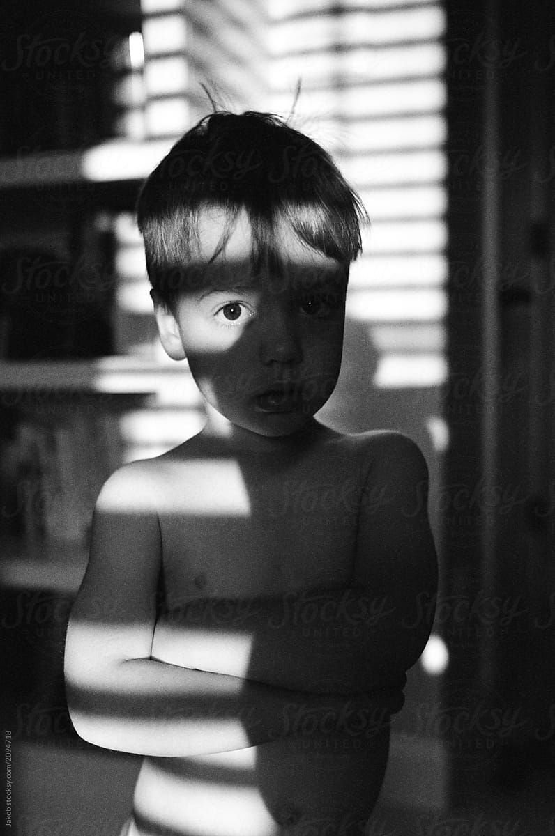 "Young Boy Standing In A Room With Shadows Falling On Him" by Stocksy ...
