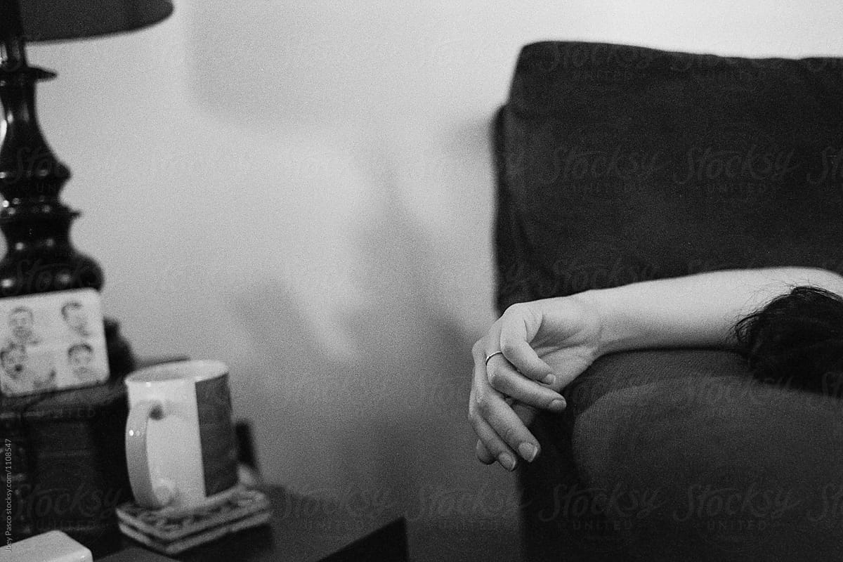 "The Hand Of A Woman Hangs Over The Armrest Of A Sofa As She Naps On A ...