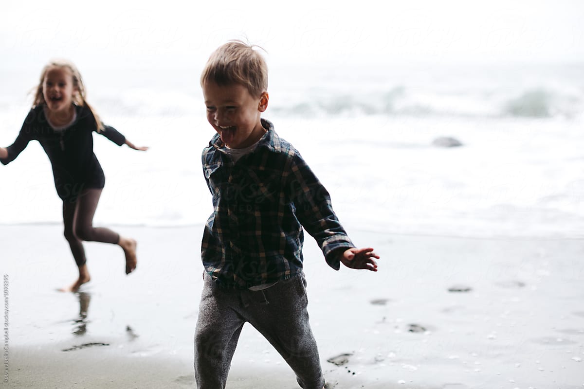 "Young Kids Running Away From Ocean Waves In Winter Or Spring" by ...