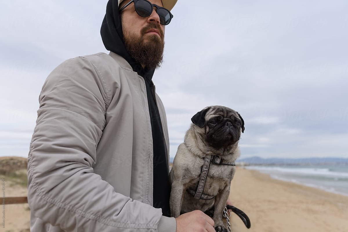 "Man Standing With Cute Pug" by Stocksy Contributor "Milles Team" - Stocksy