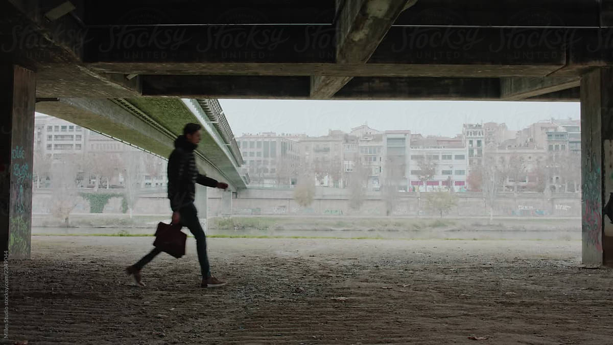 "Man With Bag Walking Under Concrete Bridge" by Stocksy Contributor ...