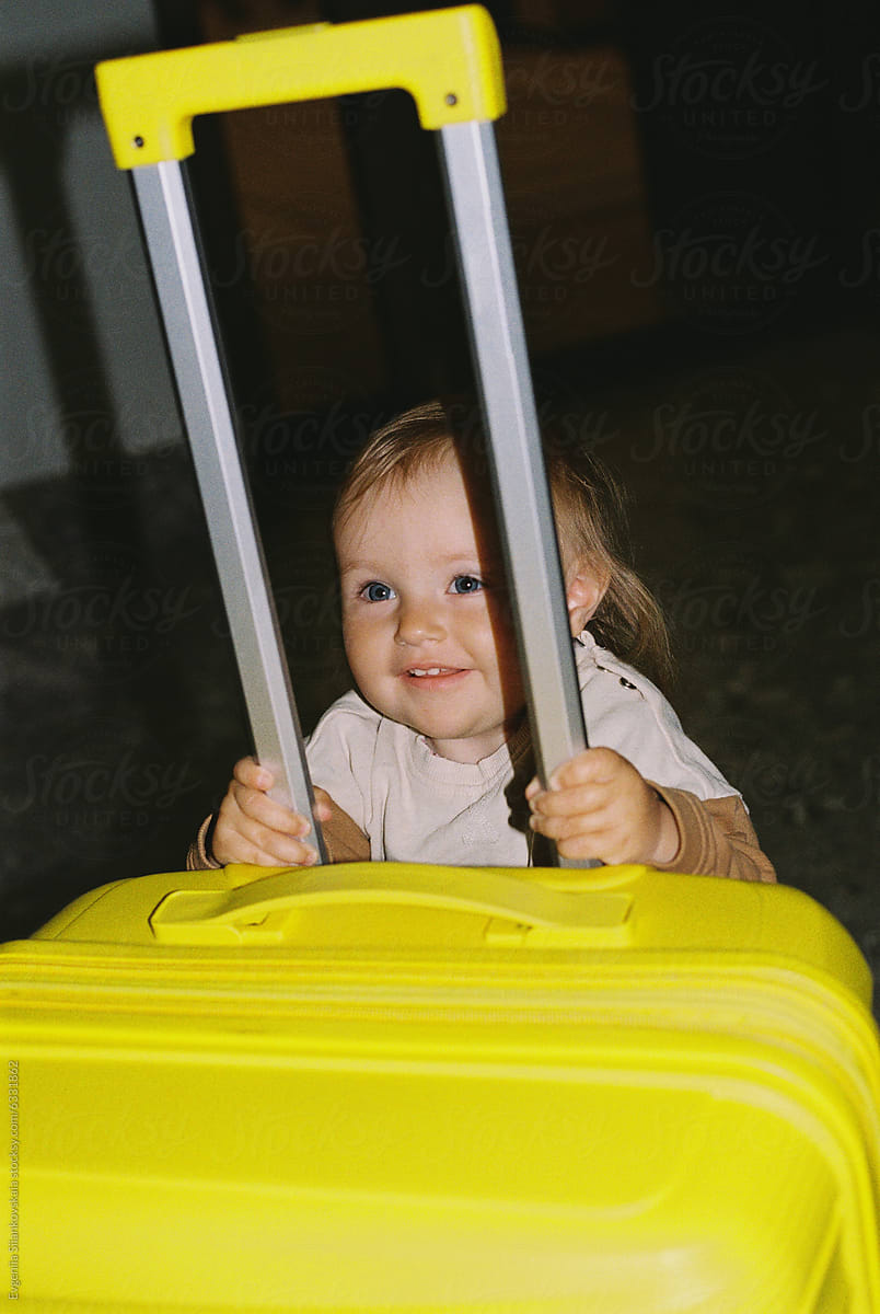 "Little Girl Peeking Out From Under Suitcase Handle And Smiling." by ...