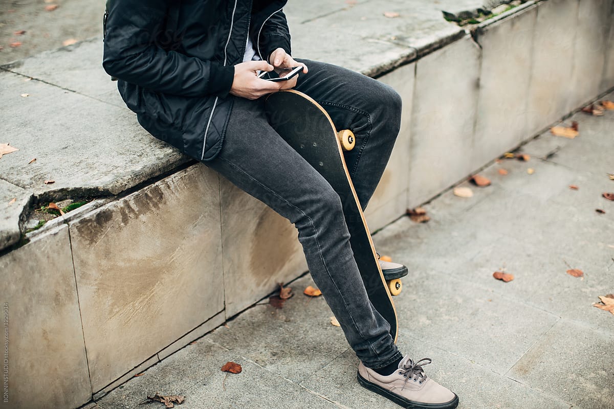 "Closeup Of A Young Man Using His Phone Sitting On The Street." by ...
