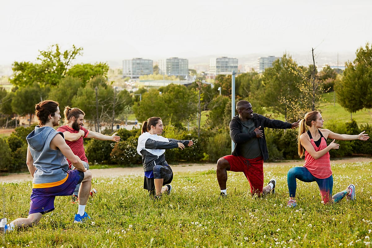 "Multiethnic Athletes Doing Stretching Exercise On Grass" by Stocksy ...