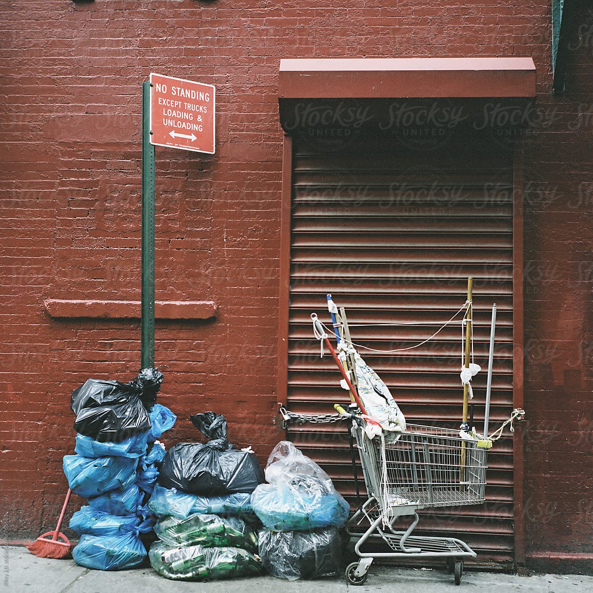 "Bags Of Trash & Shopping Cart In Front Of A Red Wall" by Stocksy ...