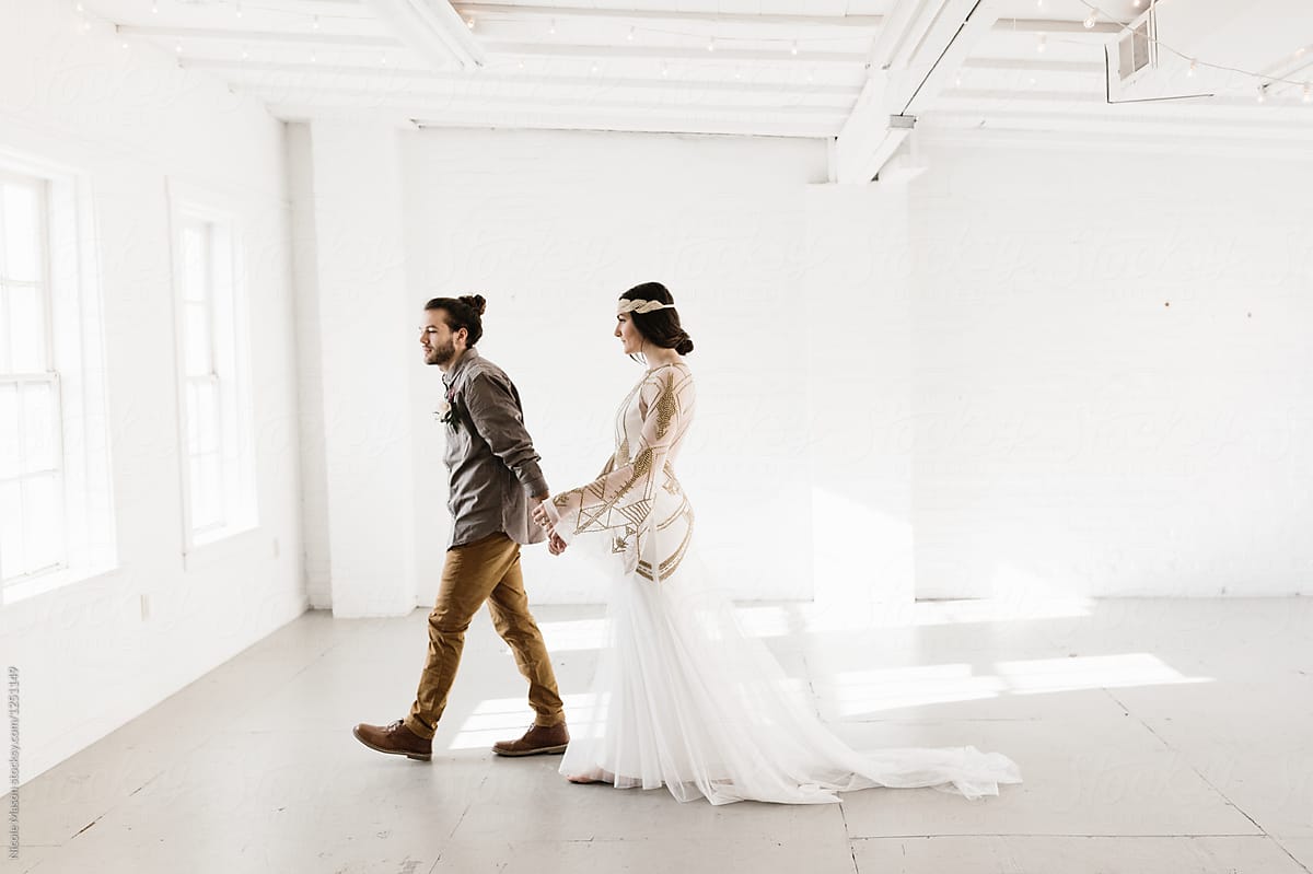 "Bride And Groom Walking Across White Warehouse" by Stocksy Contributor ...