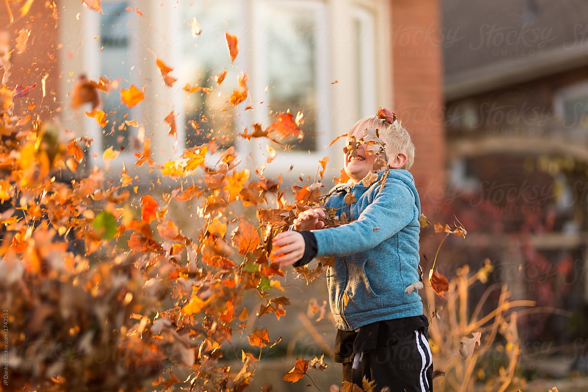 "Boy Giggles While Playing With Fallen Autumn Leaves" by Stocksy ...