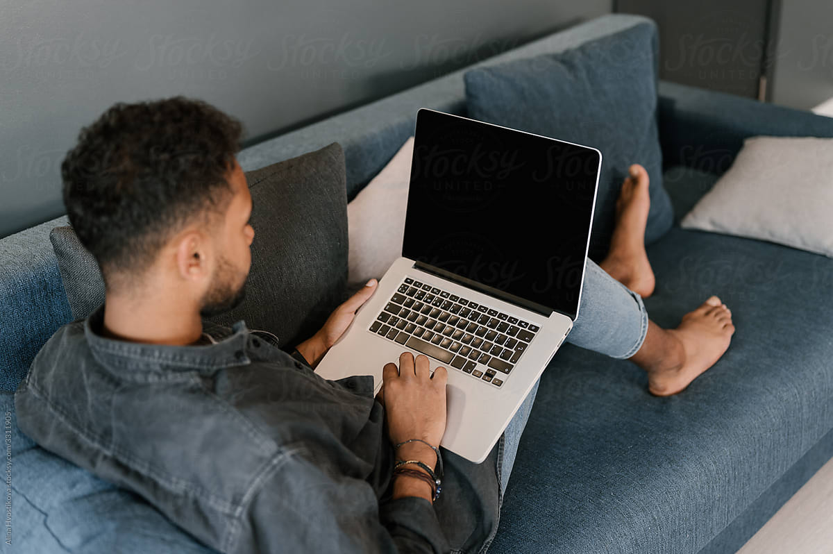 "Black Guy Browsing Laptop On Couch" by Stocksy Contributor "Alina ...
