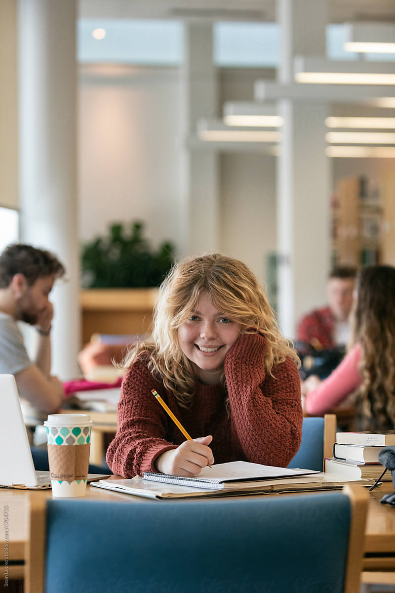 "Smiling College Student At Library Table" by Stocksy Contributor "Sean ...