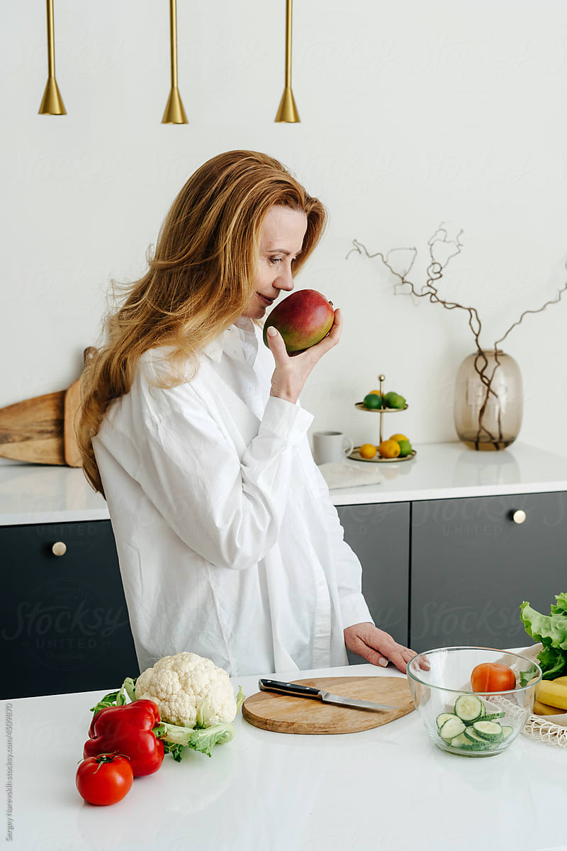 "Woman Sniffing Ripe Mango" by Stocksy Contributor "Sergey Narevskih ...