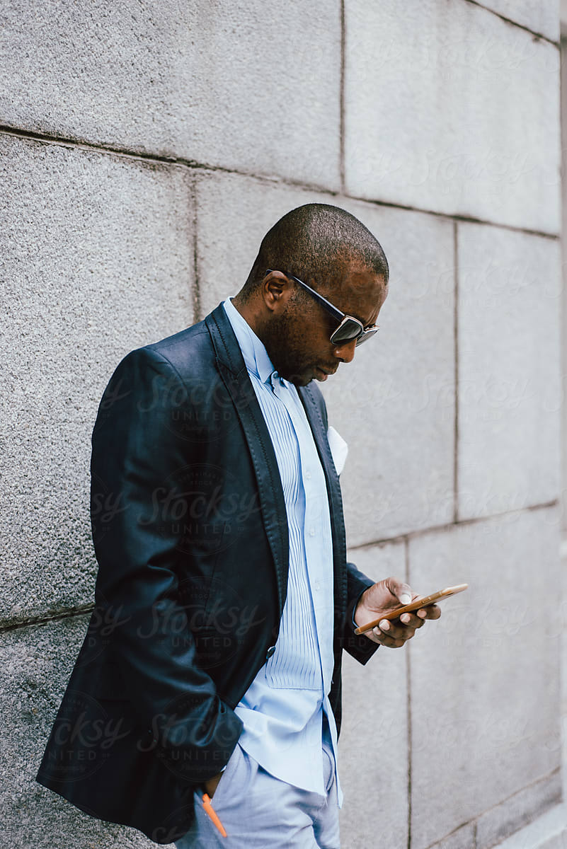 "Relaxed Black Man Using Smartphone Near Wall" by Stocksy Contributor ...