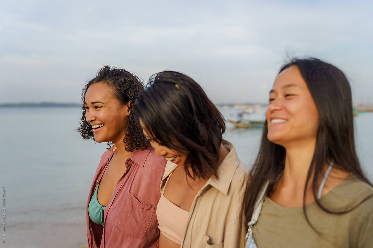 Three female tourists walking by ocean together - Stock Image - Everypixel