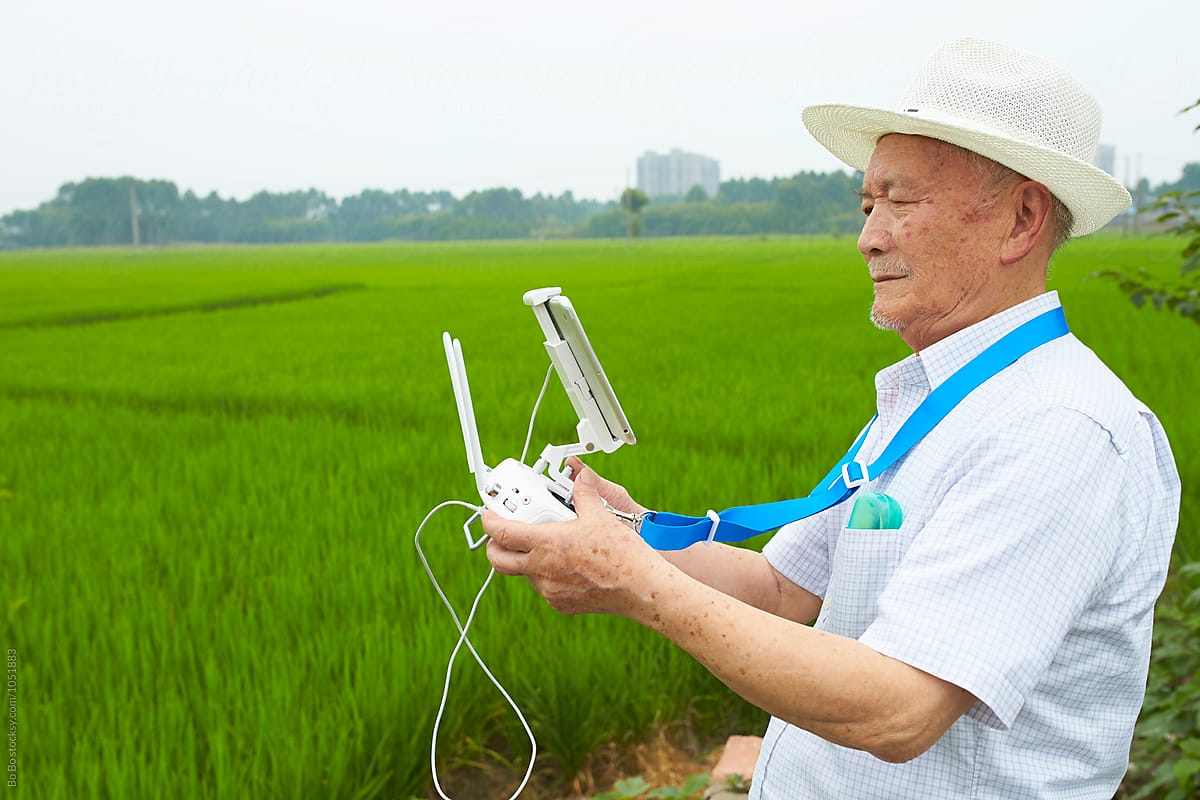 "Senior Asian Man Flying Drone" by Stocksy Contributor "Bo Bo" - Stocksy