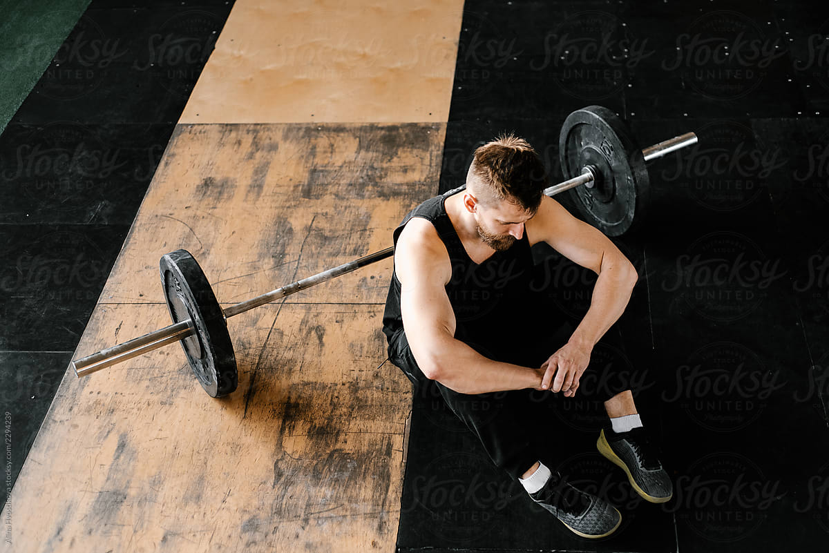 "Man Sitting On Floor With Barbell Behind" by Stocksy Contributor ...