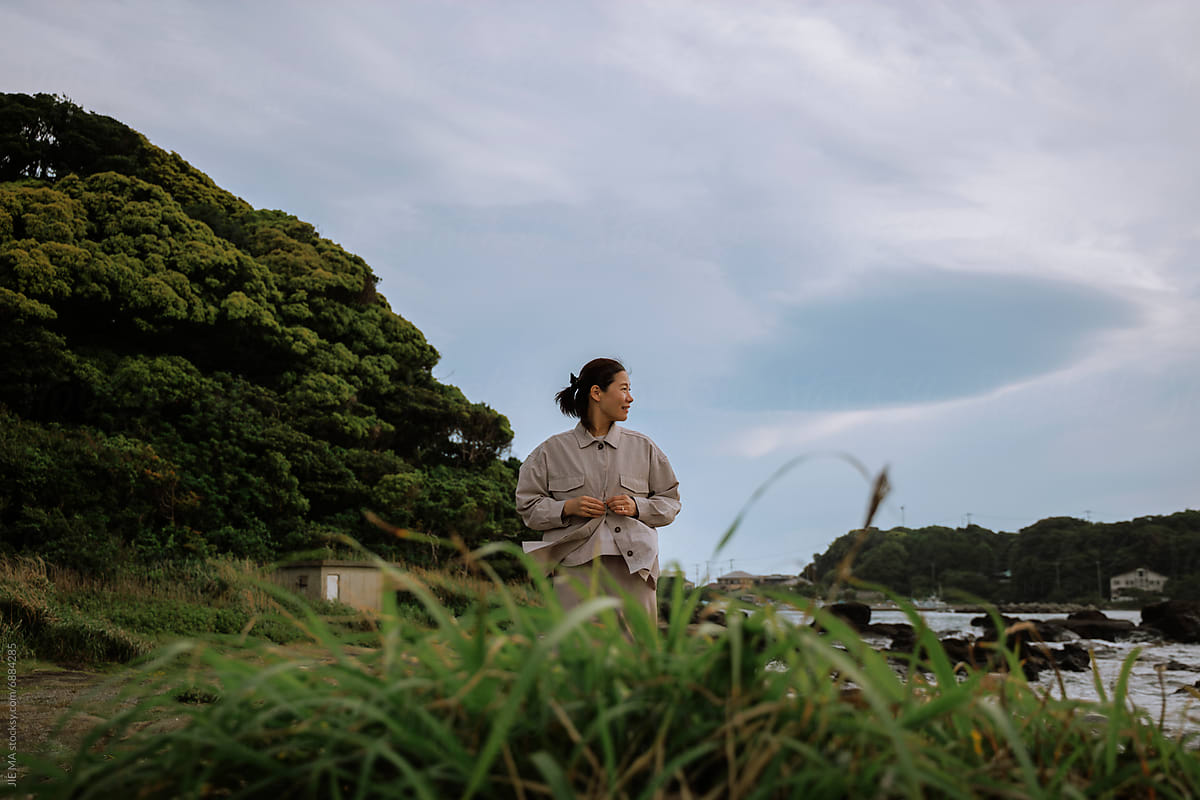 "A Woman Standing Against The Wind On A Dusk Coast." by Stocksy ...