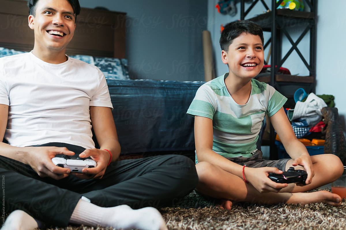 "Brothers Relaxing At Home Playing Games And Video Games." by Stocksy ...