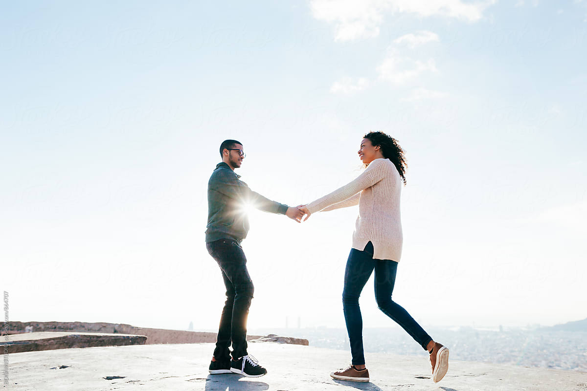 "Side View Of Mixed Race Couple Dancing Above City On A Sunny Day." by ...