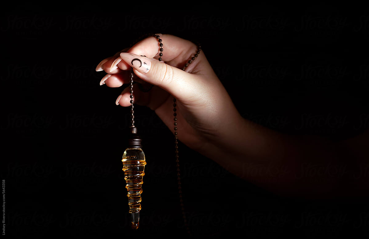"Hand Holding Pendulum" by Stocksy Contributor "Lindsey Rivera" - Stocksy