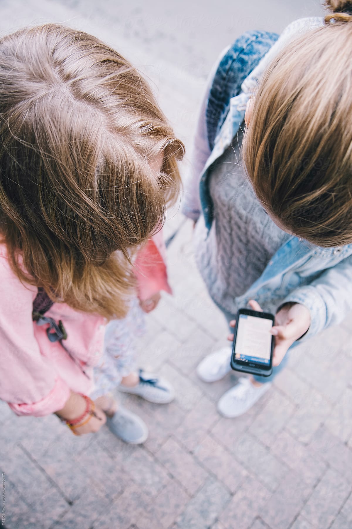 "Two Girls With Phone" by Stocksy Contributor "Danil Nevsky" - Stocksy