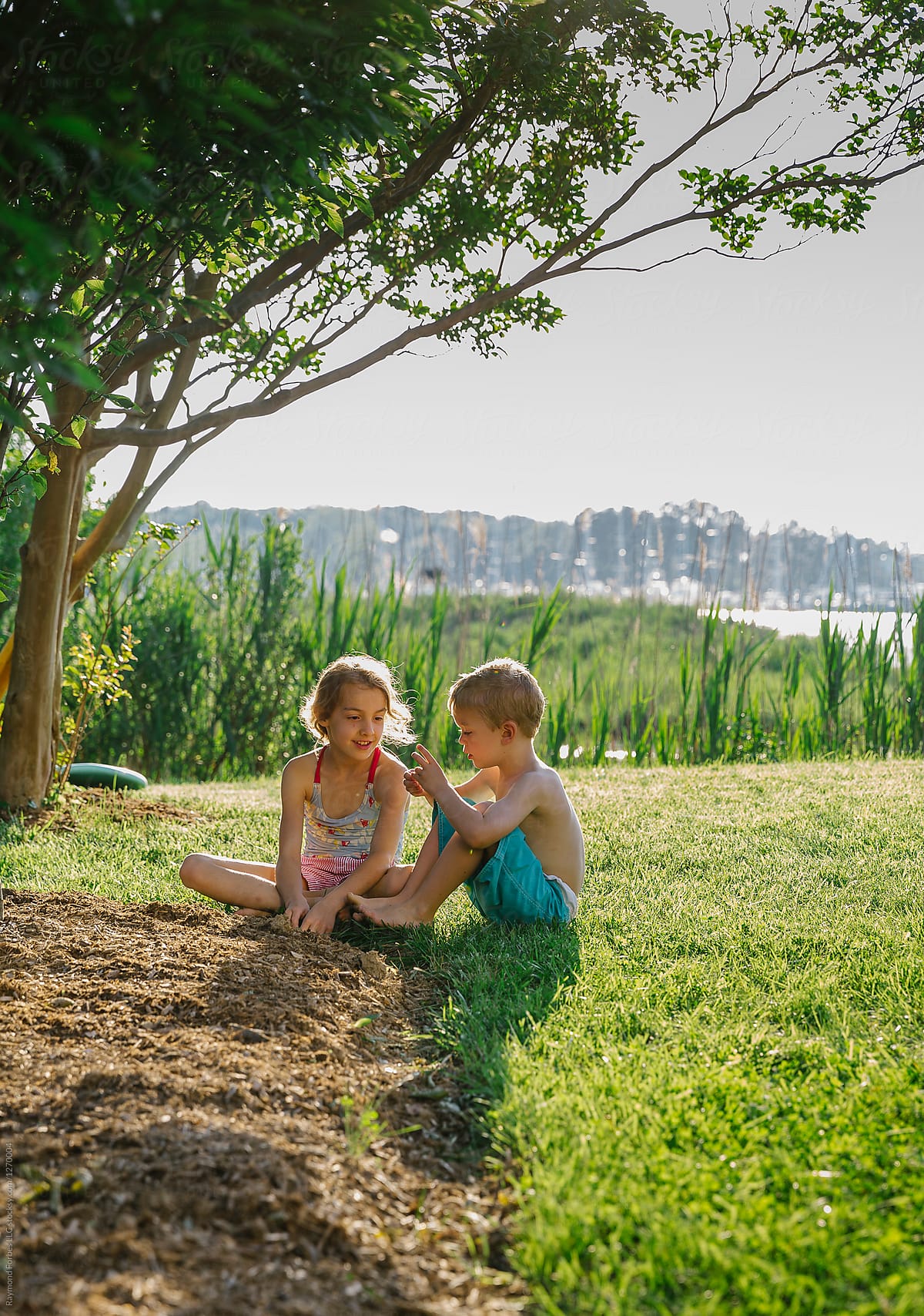 "Young Children Relaxing Inbackyard" by Stocksy Contributor "Raymond ...