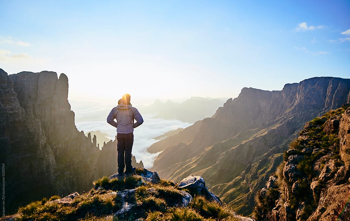 "A Male Hiker Standing On A Mountain Edge Admiring The Spired Mountain ...
