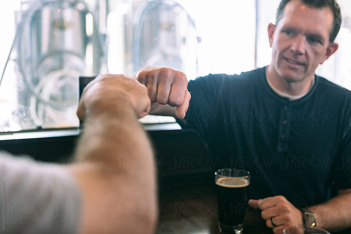 "Brewery: Guys Fist Bump Over Brews" by Stocksy Contributor "Sean Locke ...