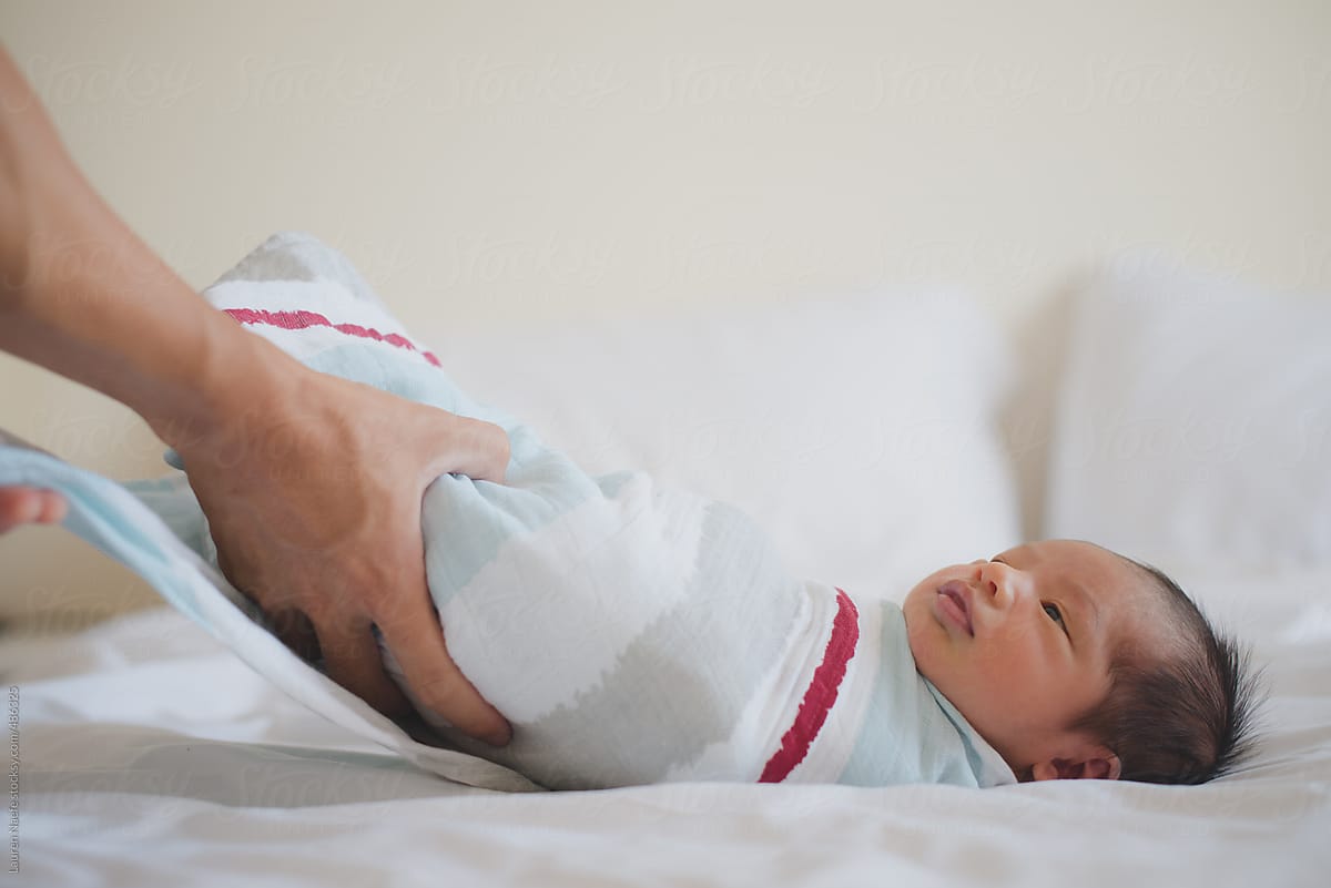 "Swaddling A Newborn Baby" by Stocksy Contributor "Lauren Lee" - Stocksy