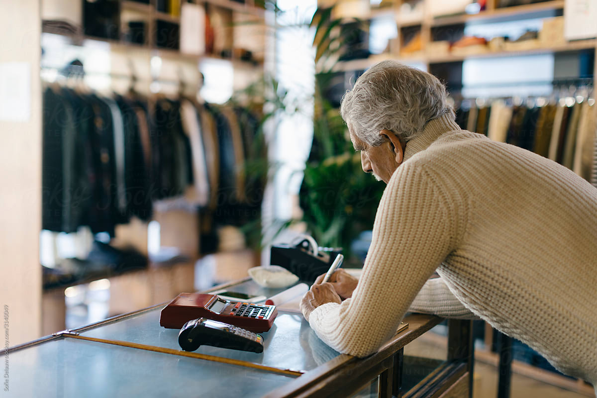 "Elderly Shop Owner At Counter Taking Notes In Notepad" by Stocksy ...