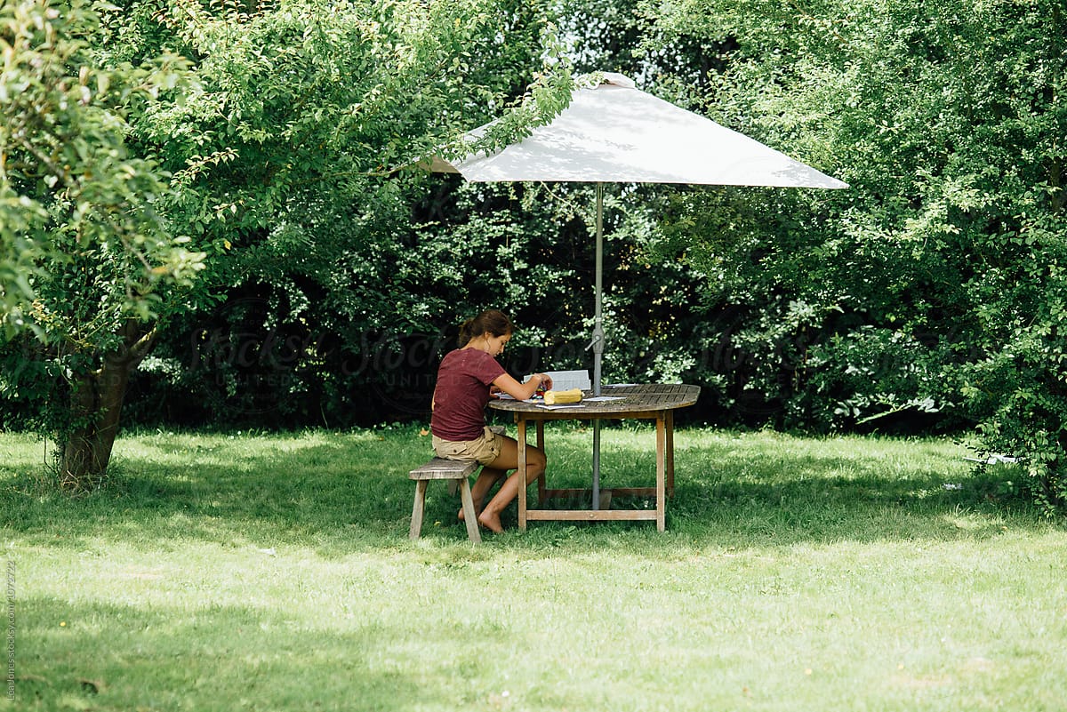 "Young Woman Sitting Under Umbrella In Her Yard" by Stocksy Contributor ...