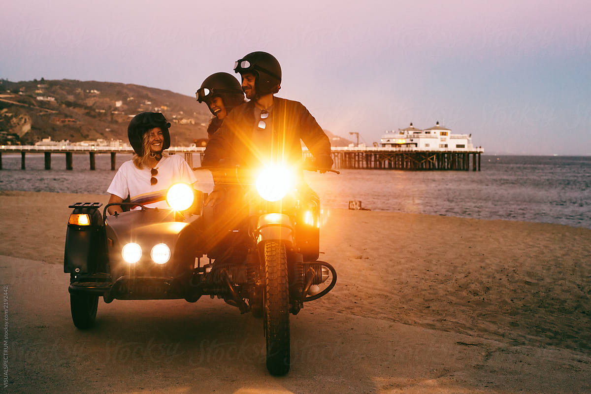 "Three Friends Laughing Together On Motorbike On California Beach" by ...