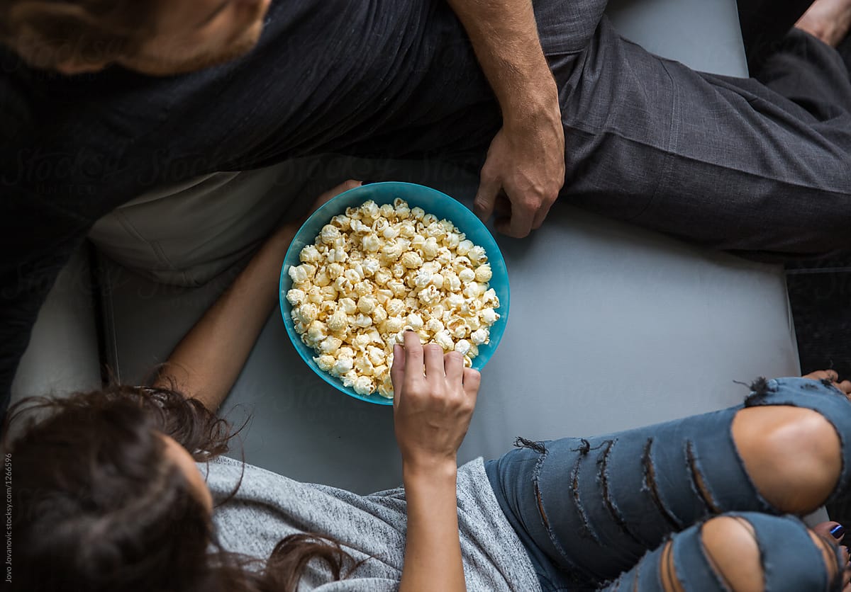 "Overhead View Of Couple Sharing Popcorn On A Couch" by Stocksy ...