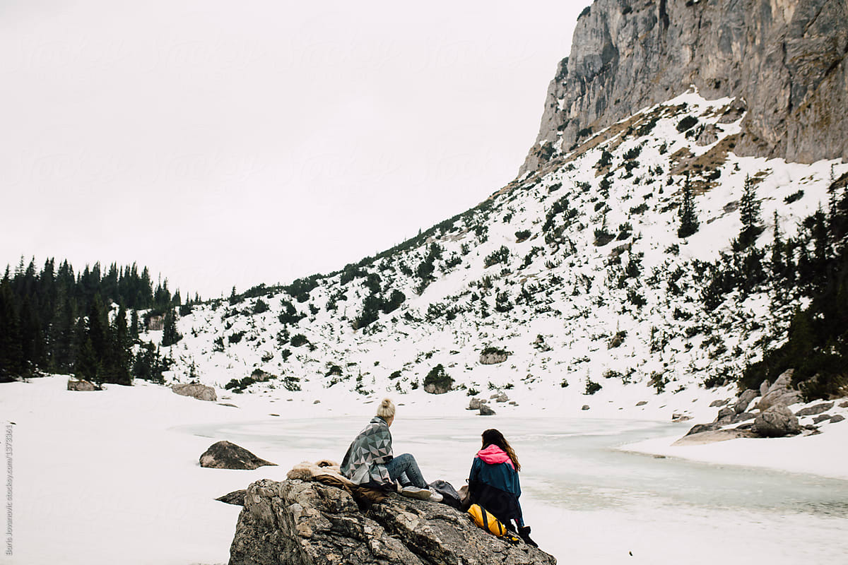 "Women Sitting Next To The Frozen Lake" by Stocksy Contributor "Boris ...