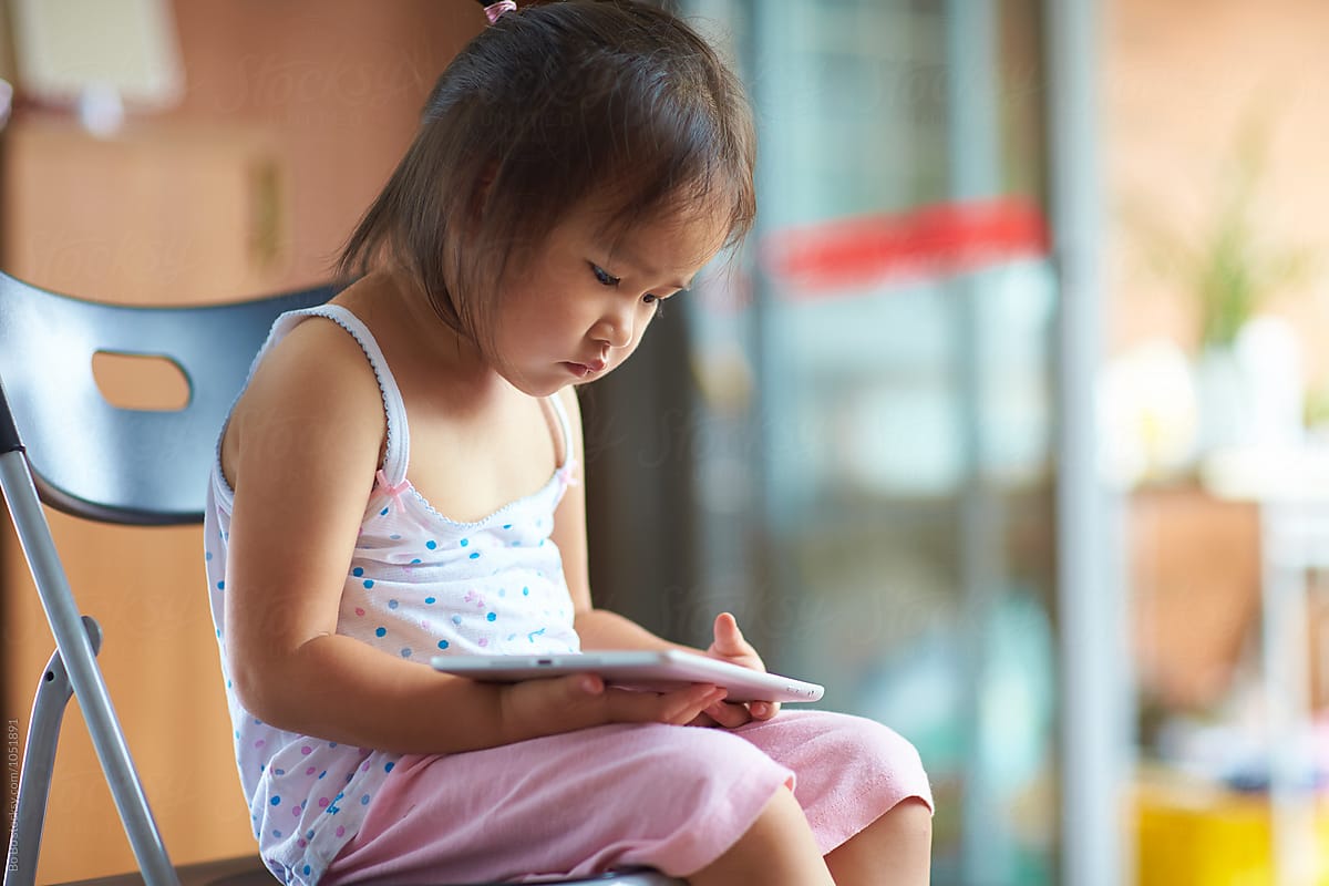 "Little Girl Using Tablet Indoor" by Stocksy Contributor "Bo Bo" - Stocksy